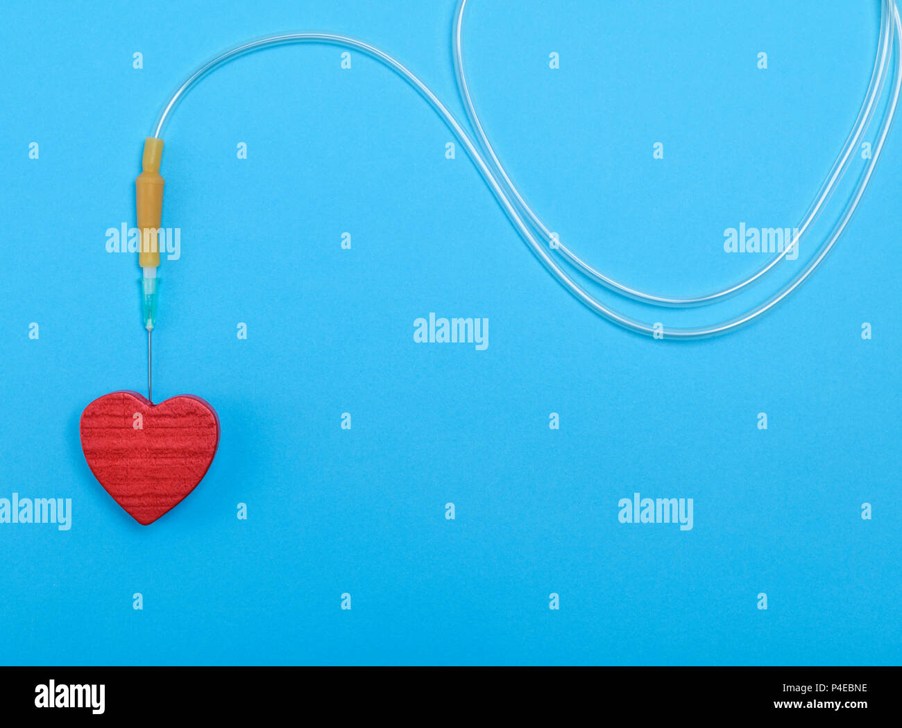 plastic catheter with needle and red heart on blue background, copy ...