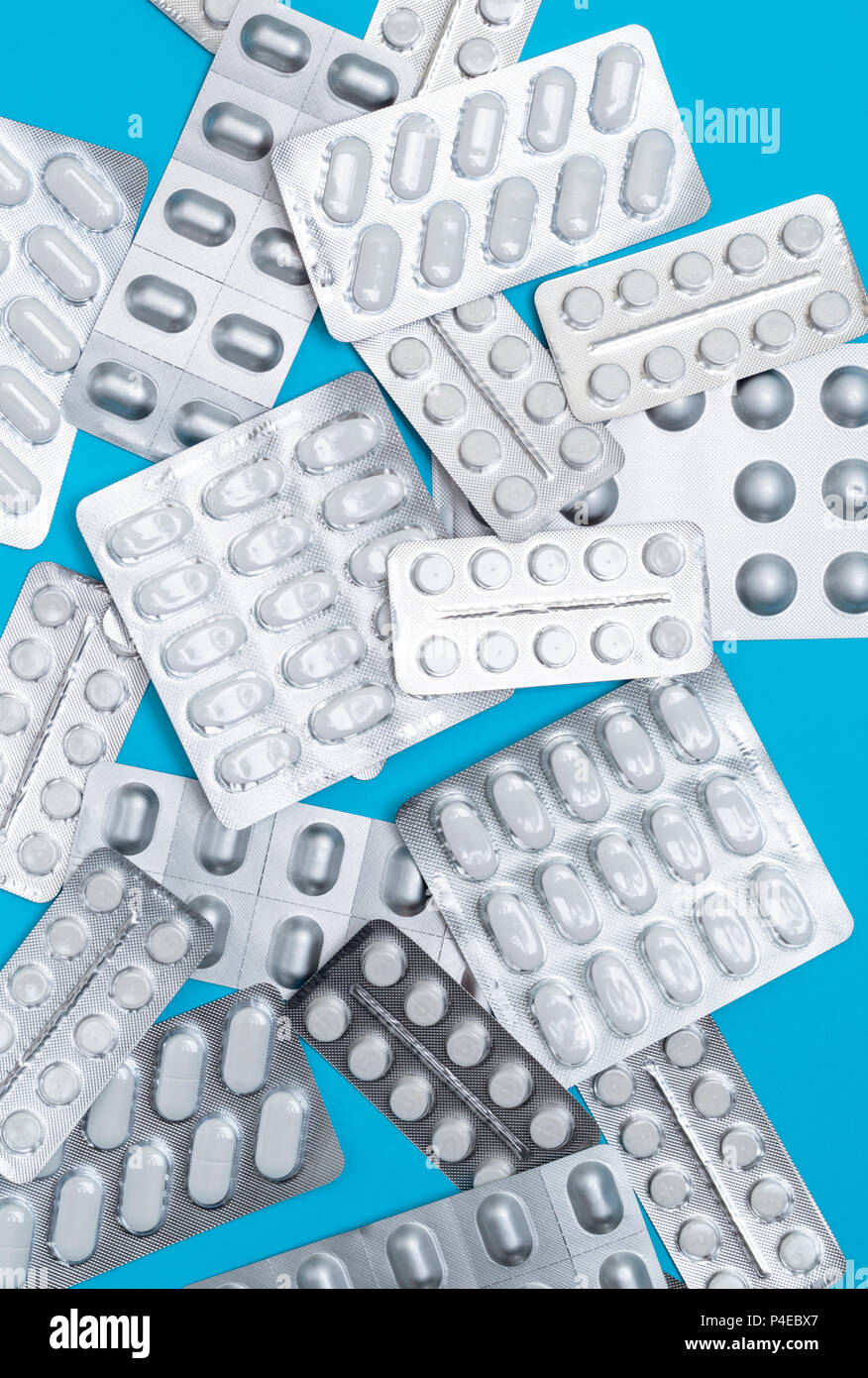 scattered various pills in gray packaging on a blue background, top ...