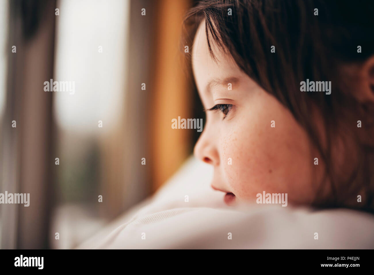 Portrait of a girl leaning on couch looking out of a window Stock Photo ...