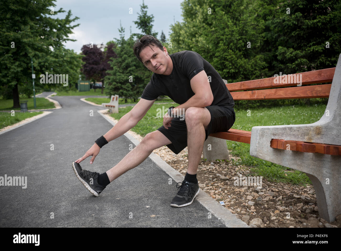 Man sitting on a bench stretching before going running Stock Photo - Alamy