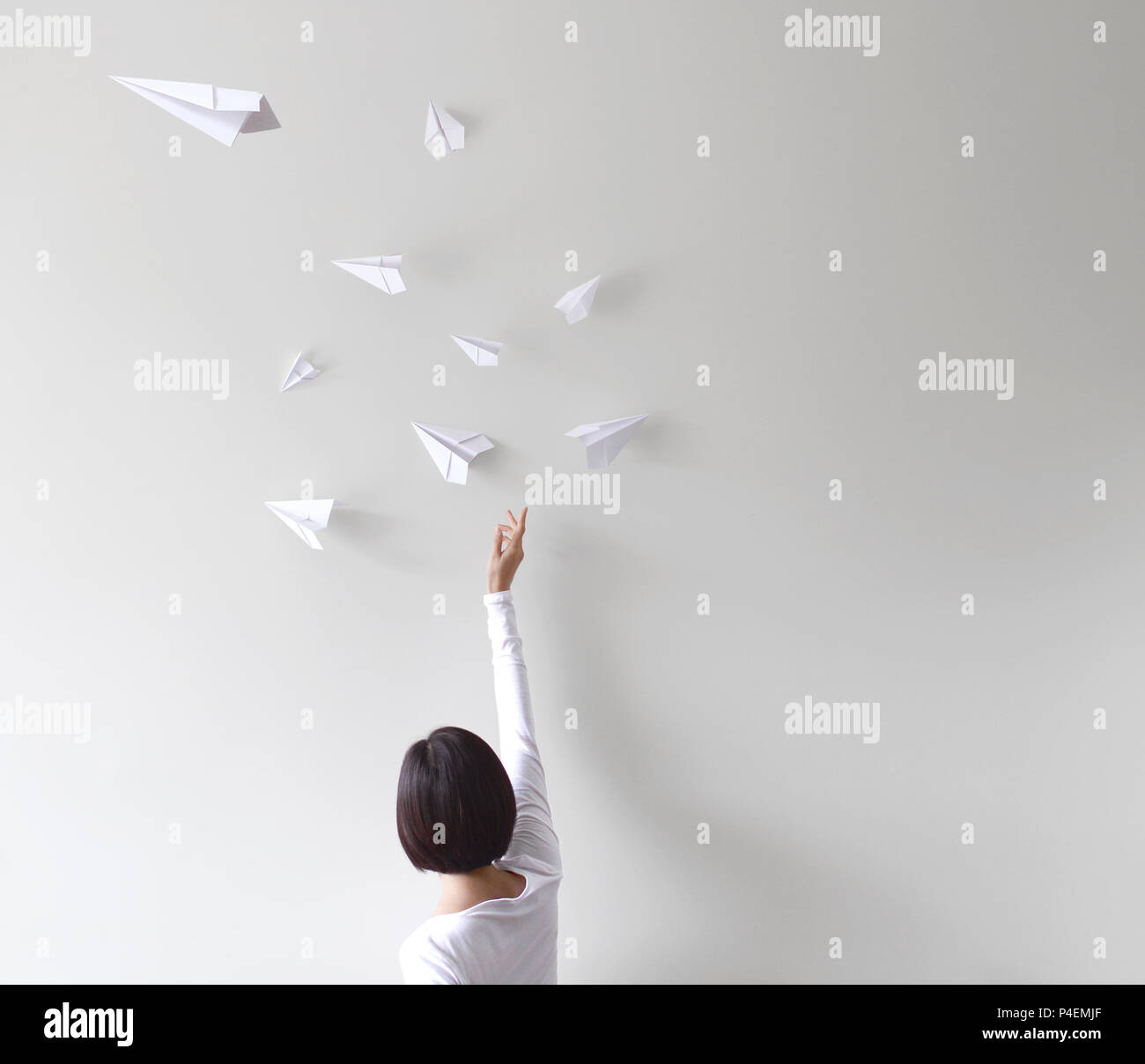 Rear view of woman throwing white paper airplanes in the air Stock ...