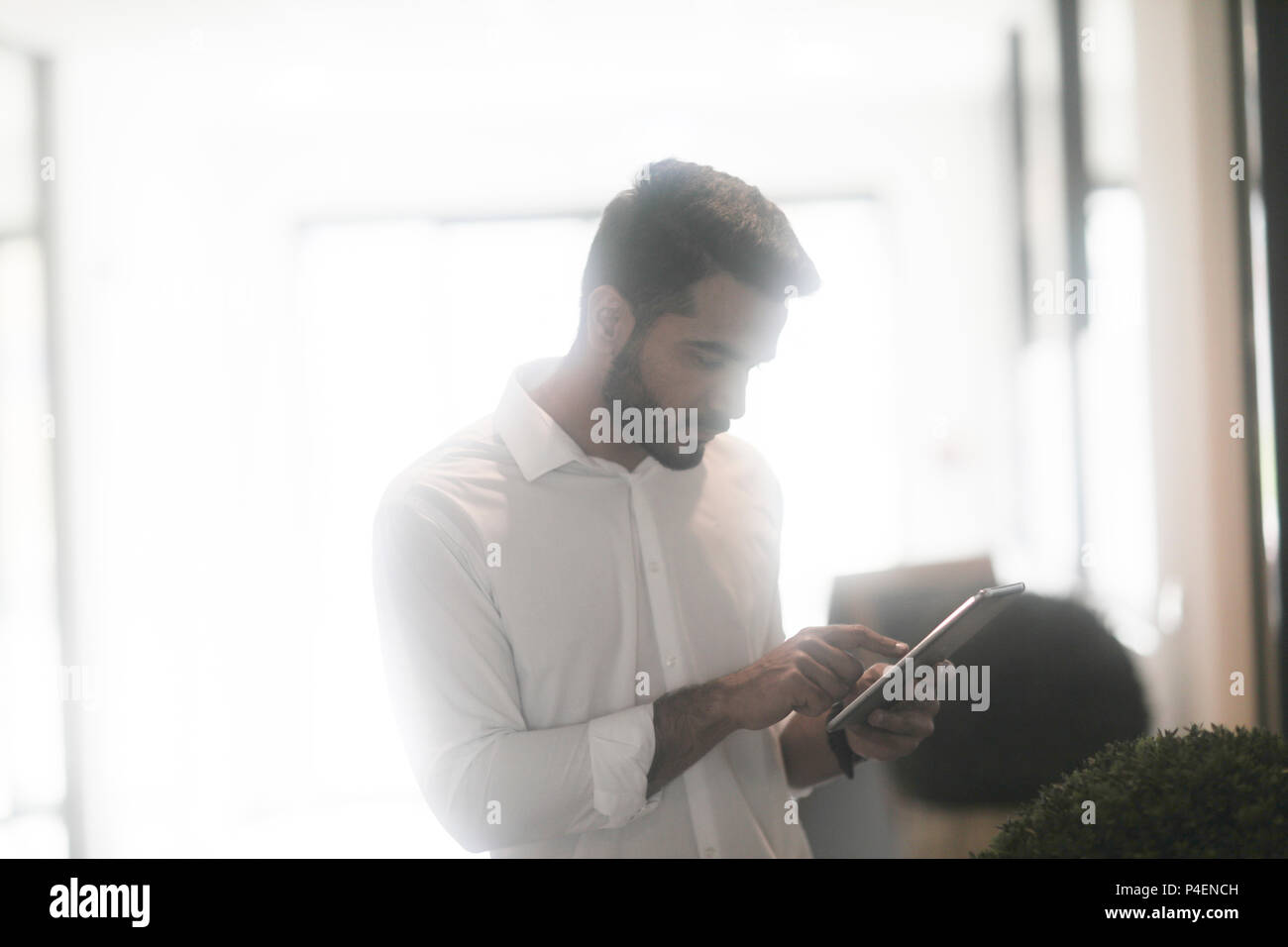 Man standing in an office using a digital tablet Stock Photo - Alamy