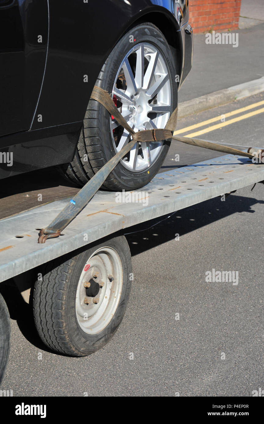 Dark car secured onto the back of a car trailer Stock Photo - Alamy
