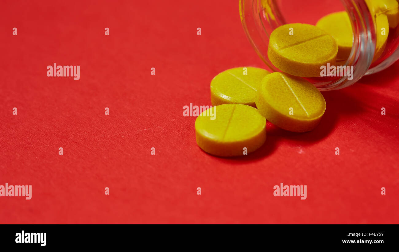 Pills spilling out of pill bottle on red. Top view with copy space ...
