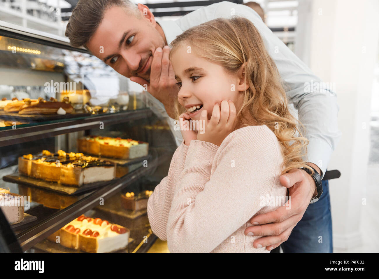 father and little daughter choosing cake on display at cafe Stock Photo ...