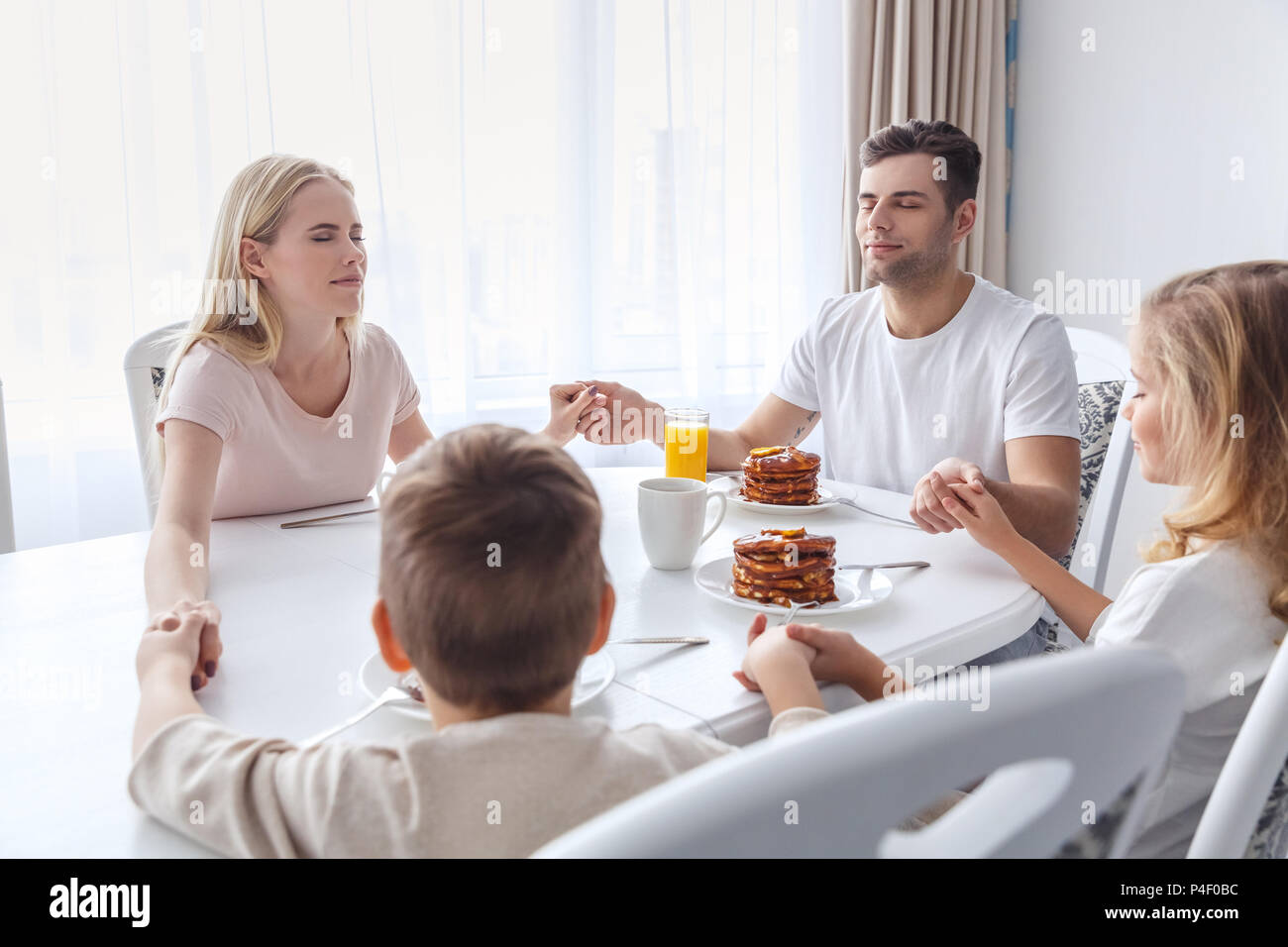 christian family praying before breakfast and holding hands Stock Photo ...