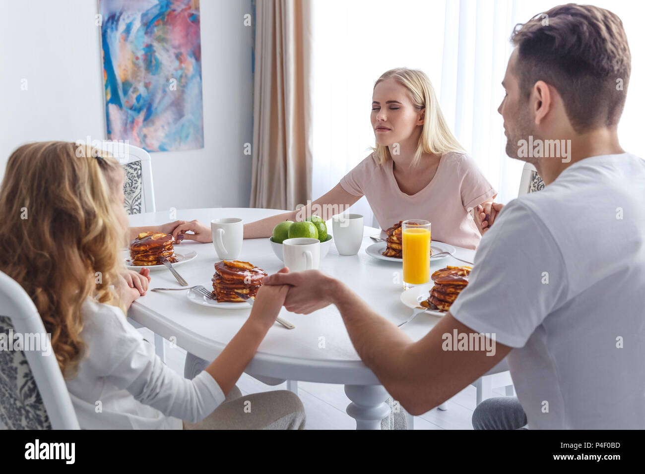 christian family praying before breakfast and holding hands Stock Photo ...
