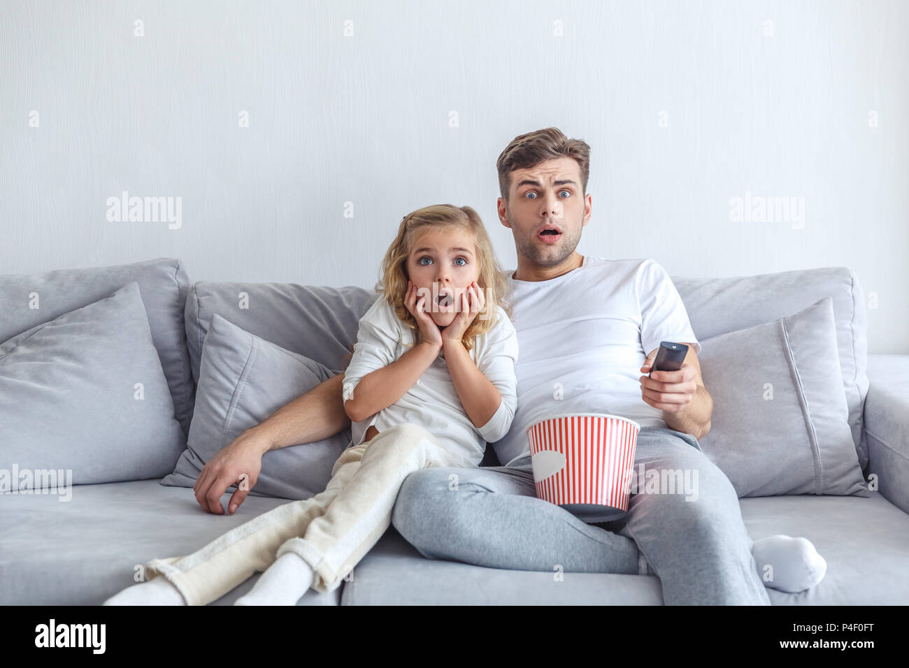 frightened father and daughter watching scarry movie at home Stock ...