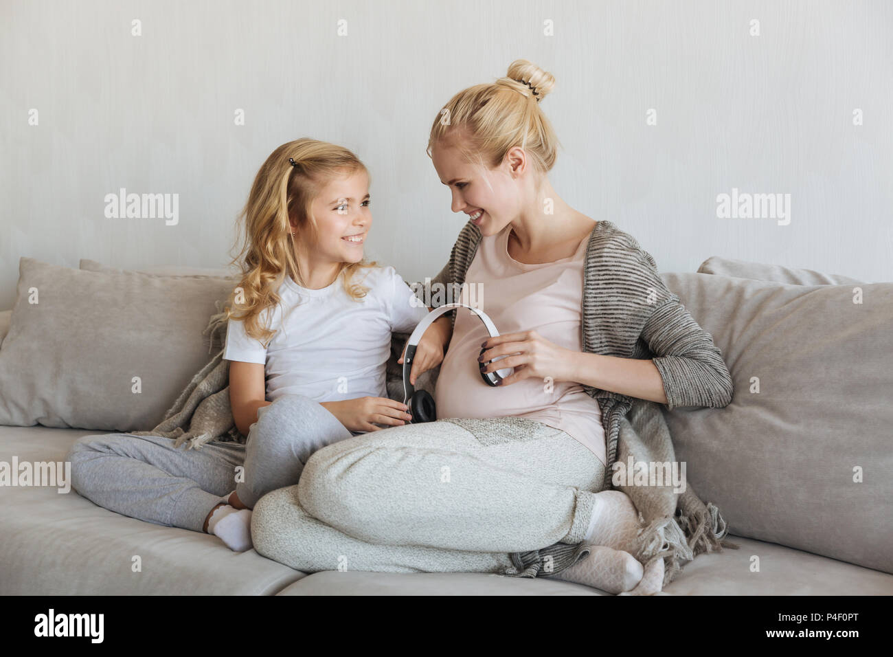 smiling pregnant mother and daughter giving to listen music to embryo ...