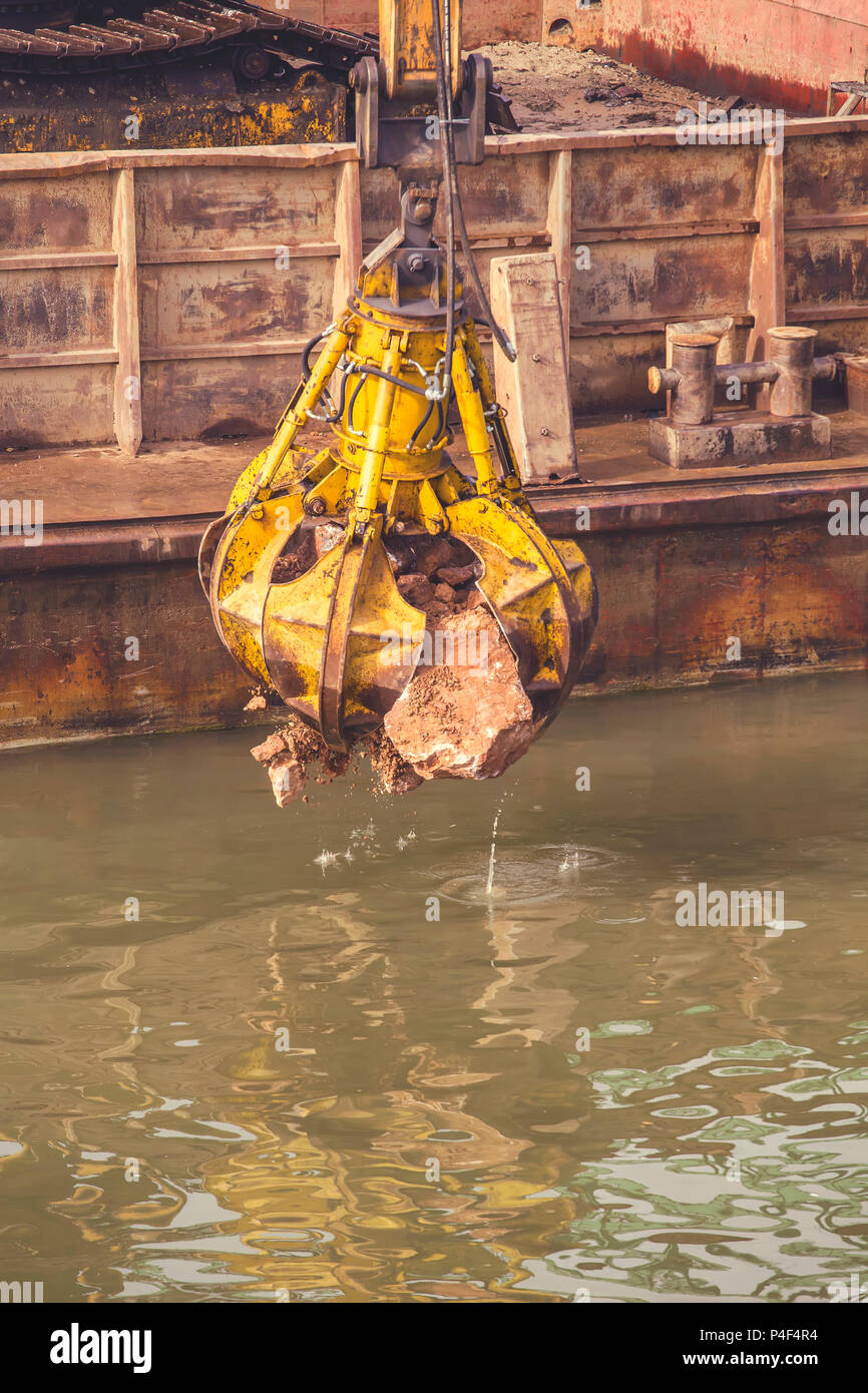 Excavator on barge with hydraulic rotator stone grab in action from ...