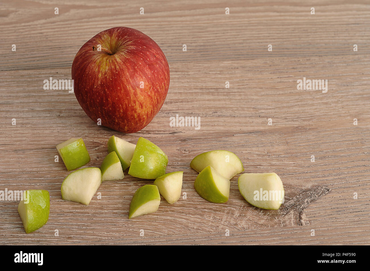 A red apple displayed with a cut up green apple Stock Photo - Alamy