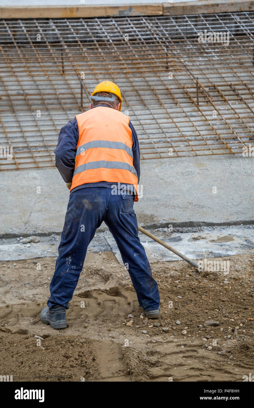 Worker with rake working on ground leveling at construction site Stock ...