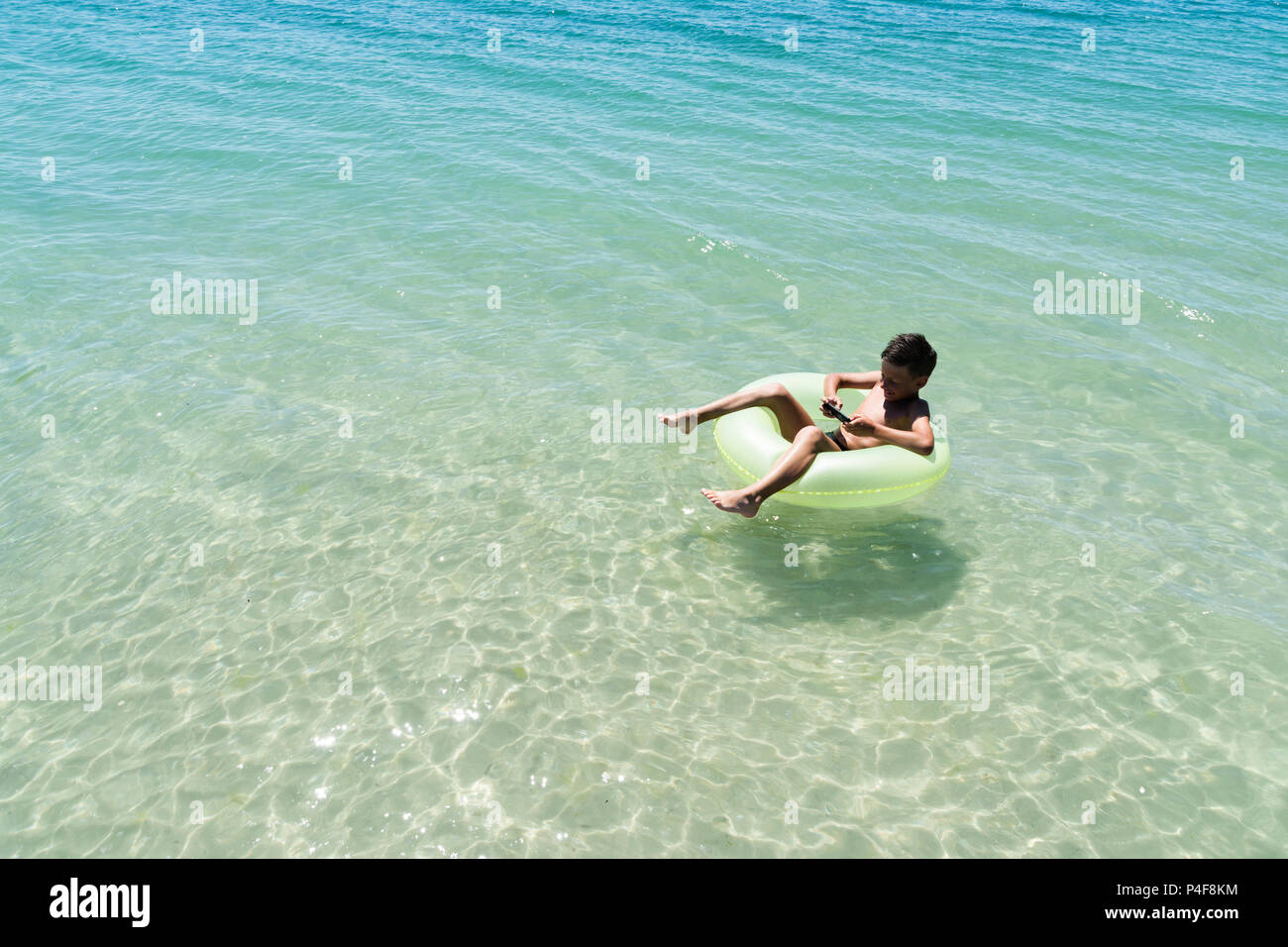 Boy swimming in inflatable ring with smart phone Stock Photo - Alamy