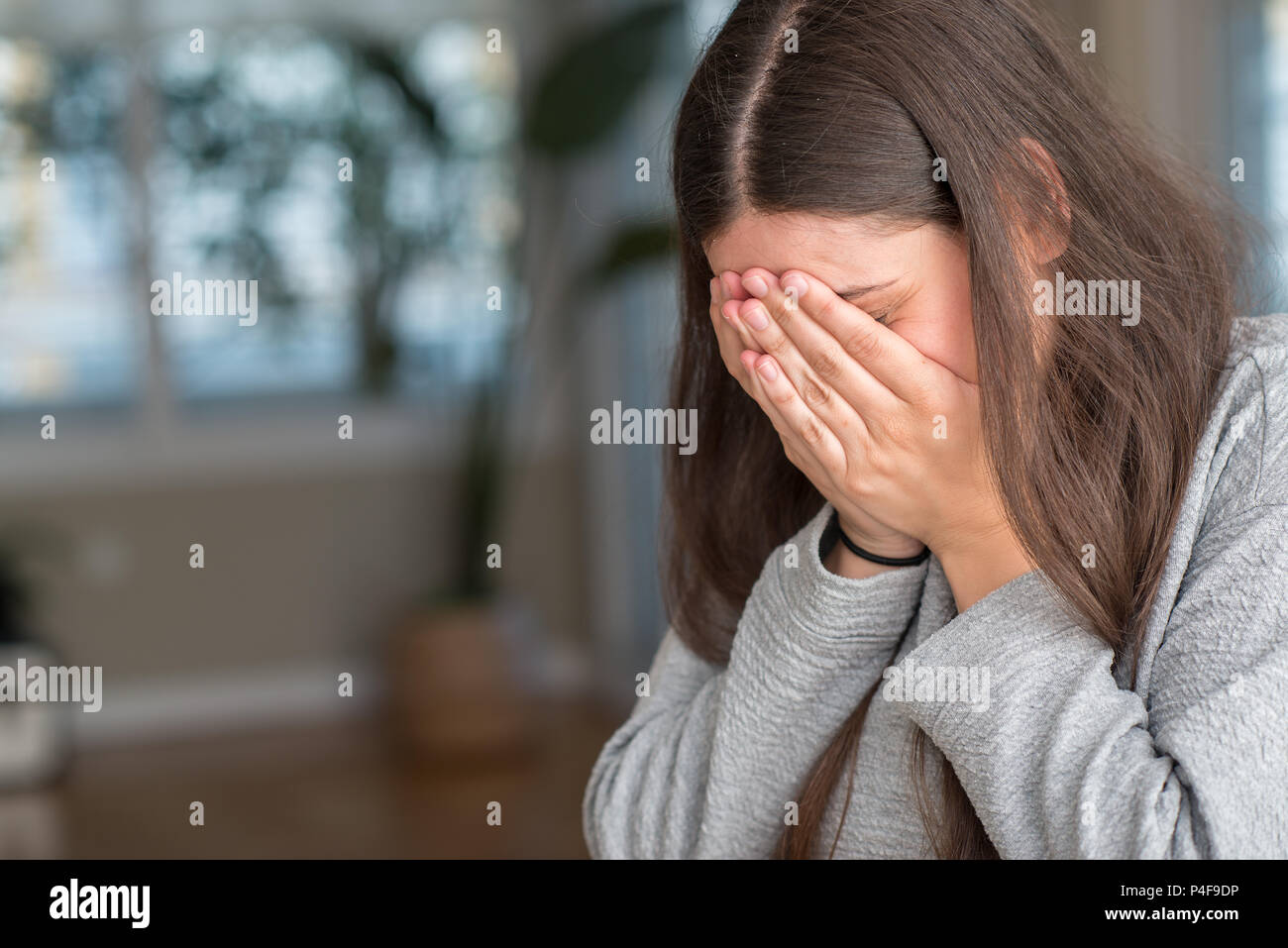 Young beautiful woman at home with sad expression covering face with ...