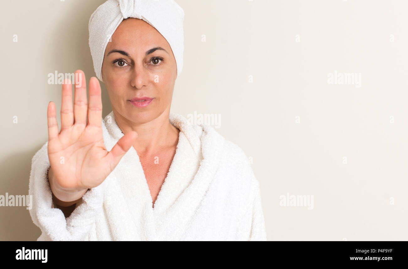 Beautiful middle age woman, wet hair wearing a towel with open hand ...