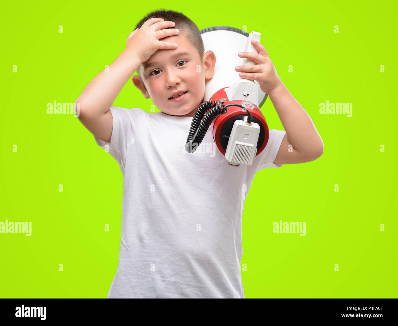 Dark haired little child holding megaphone stressed with hand on head ...