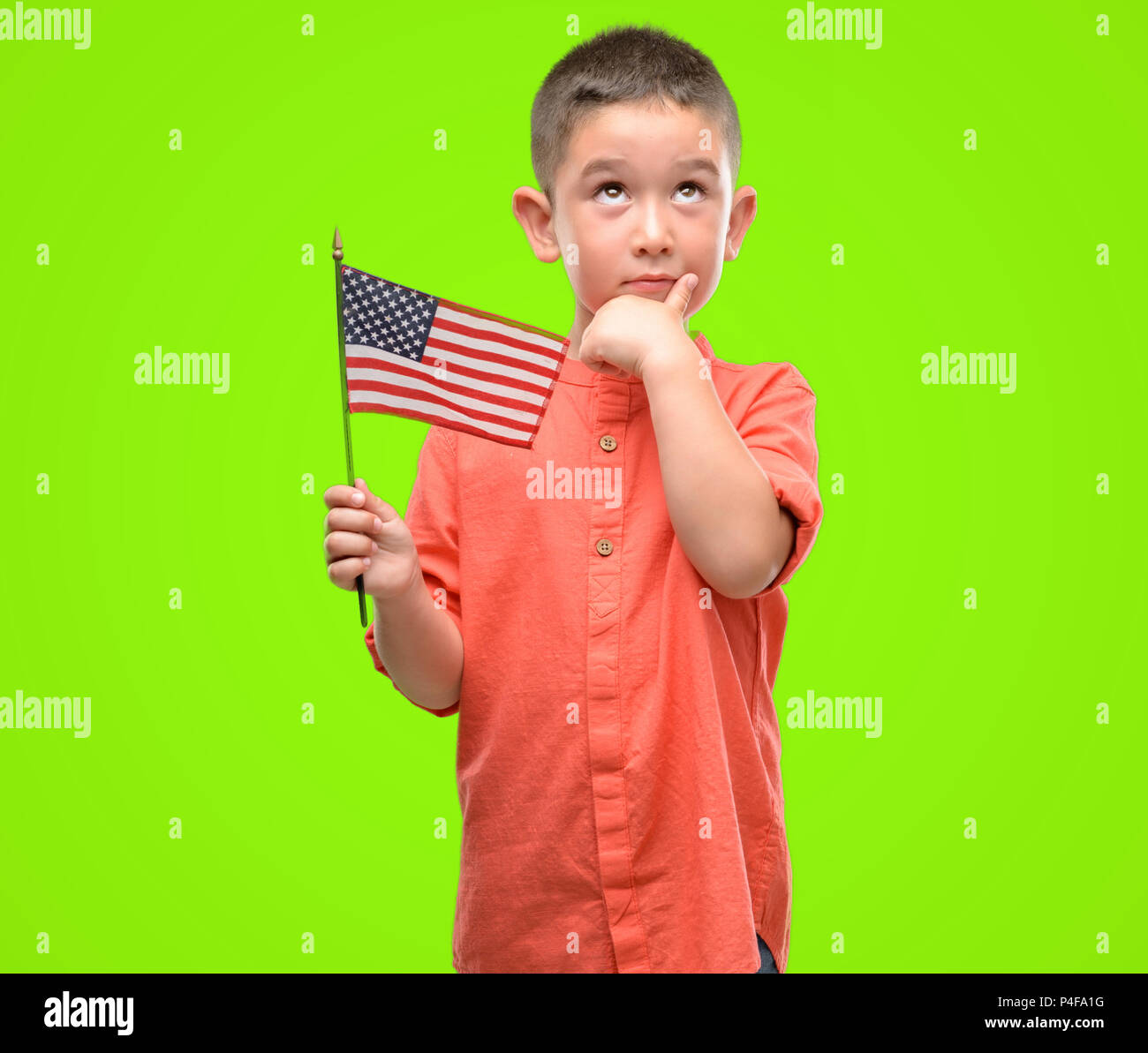 Dark haired little child holding United States flag serious face ...
