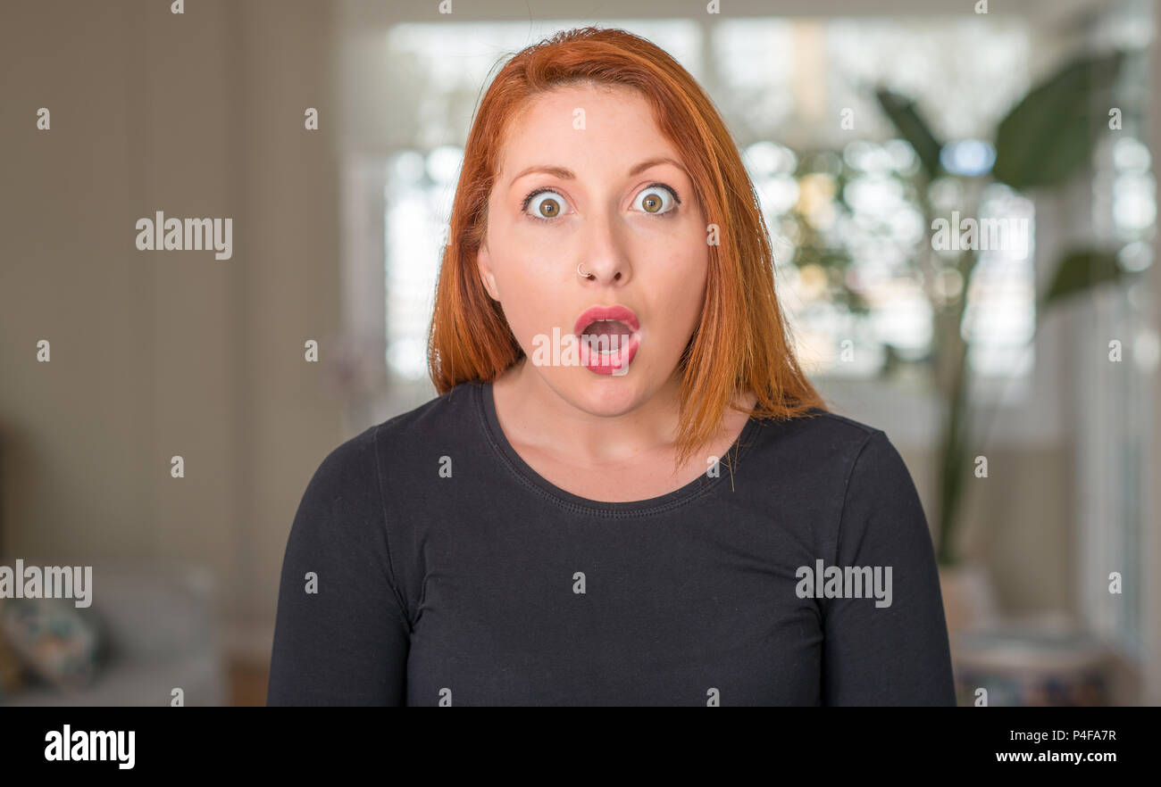 Redhead woman at home scared in shock with a surprise face, afraid and ...