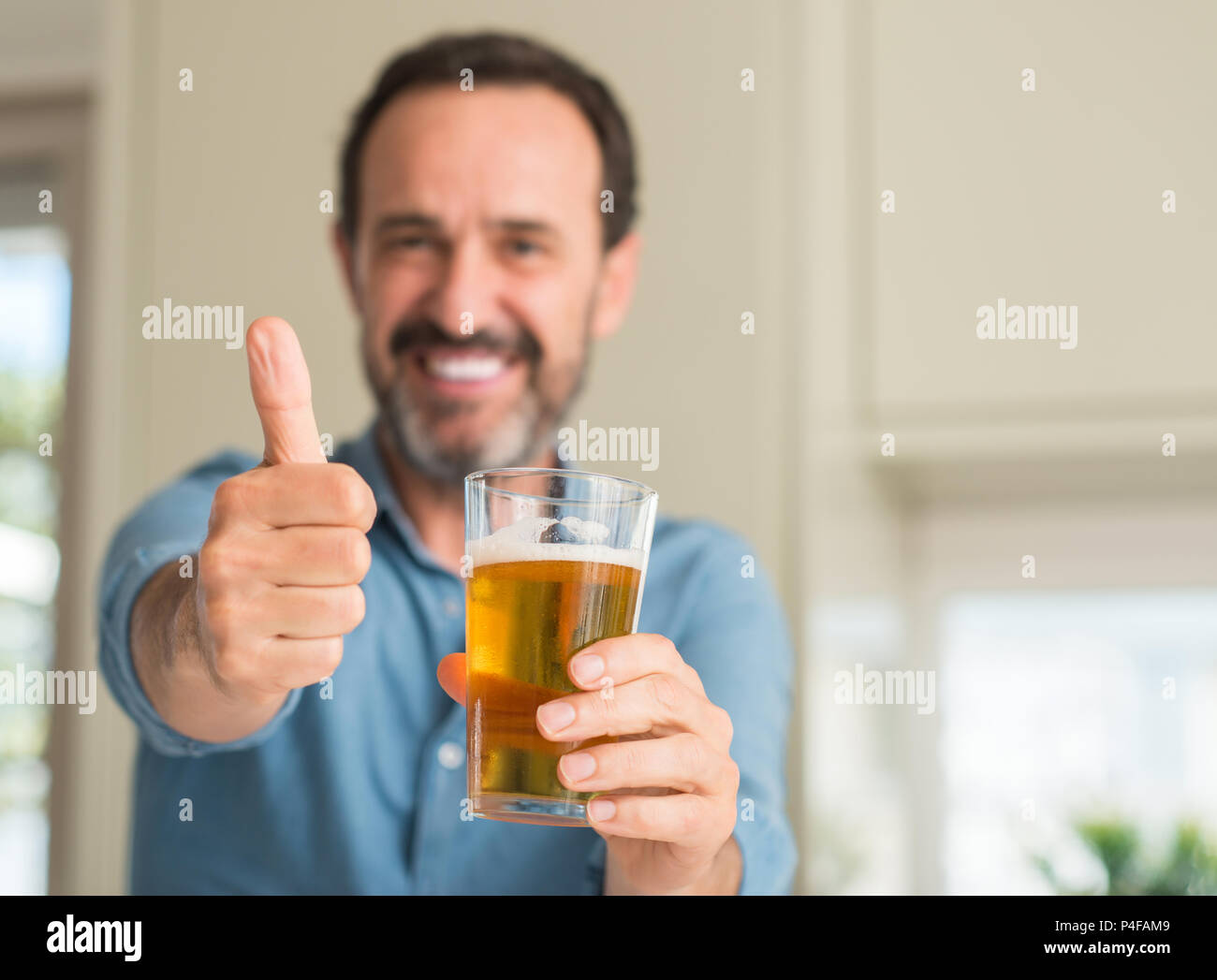 Middle age man drinking beer happy with big smile doing ok sign, thumb ...