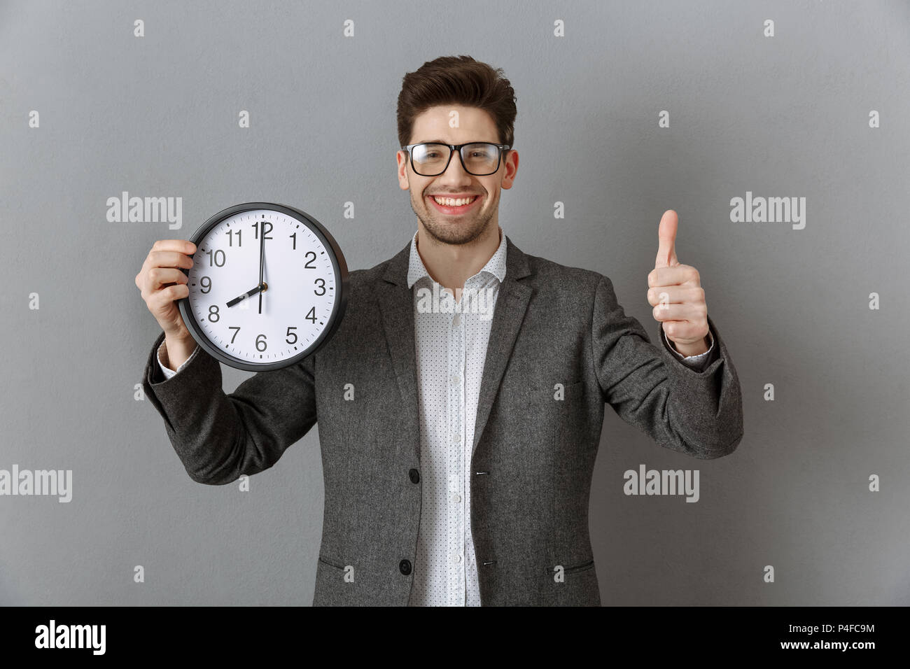 portrait of smiling businessman with clock in hand showing thumb up on ...