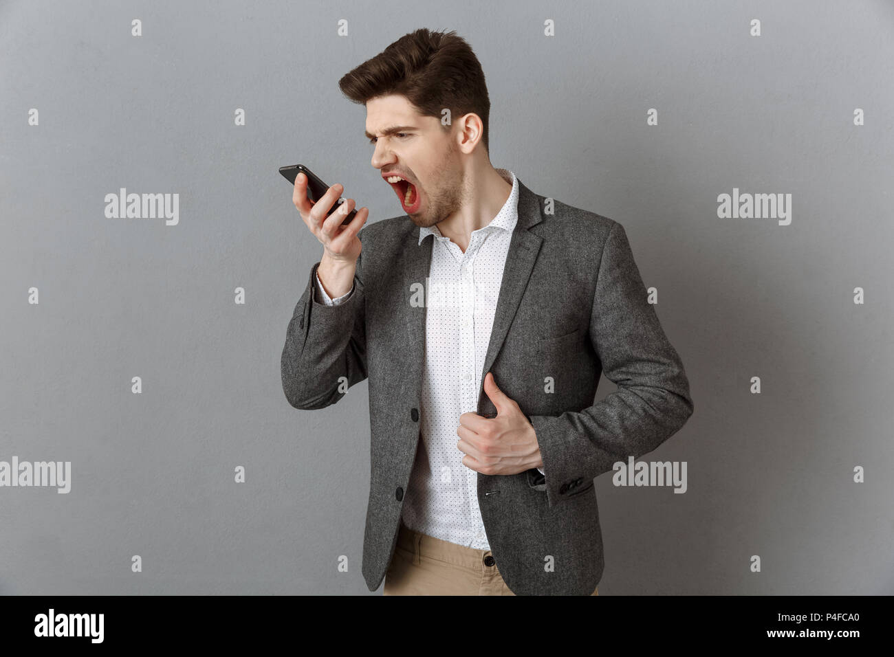 portrait of angry businessman screaming while talking on smartphone ...