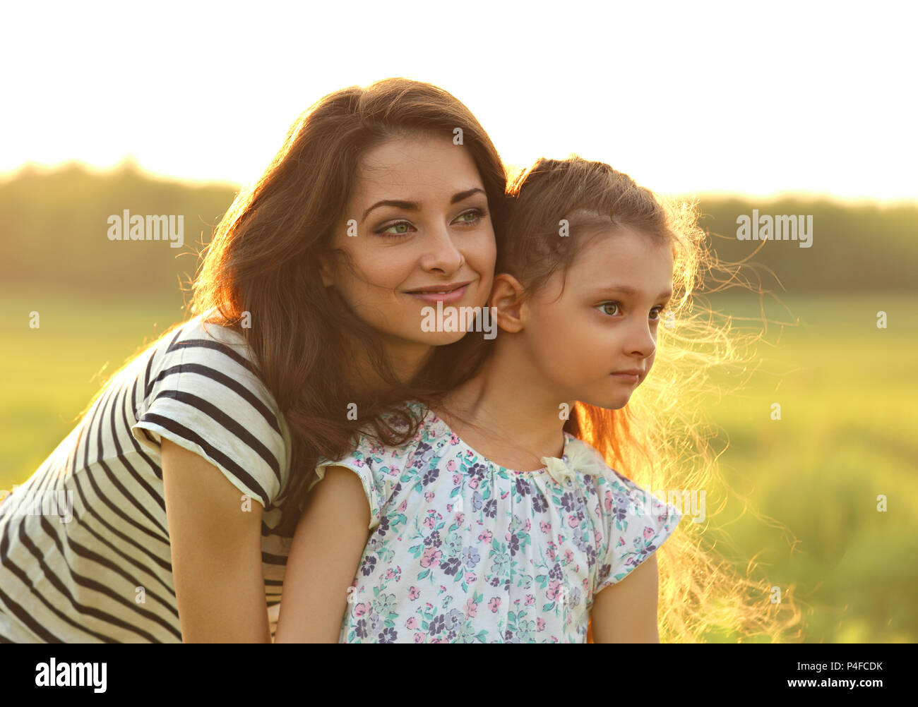 Emotional calm mother hugging her relaxing kid girl with loving eyes on ...