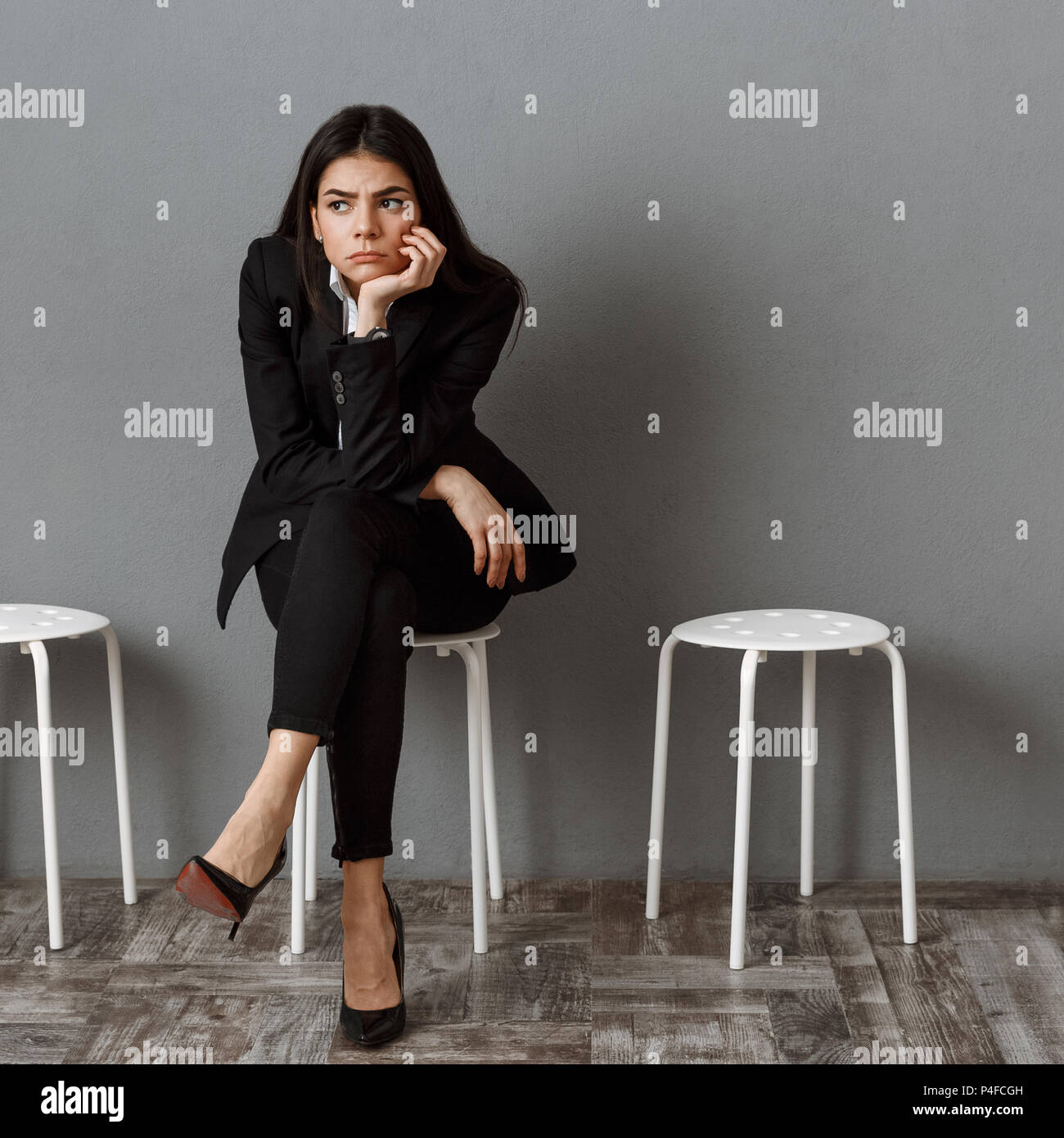 tired businesswoman in suit looking away while waiting for job ...