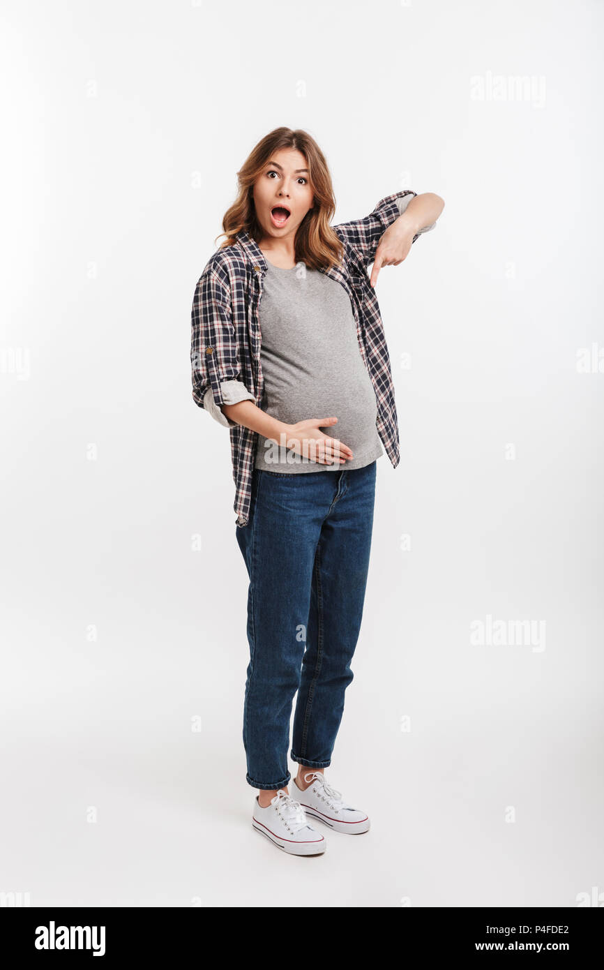 excited pregnant woman pointing at tummy isolated on grey Stock Photo ...