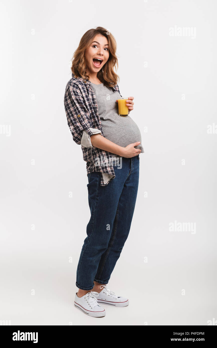 excited pregnant woman holding glass with juice and looking at camera ...