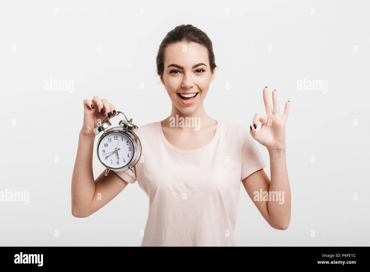 beautiful girl showing ok gesture and holding alarm clock isolated on ...