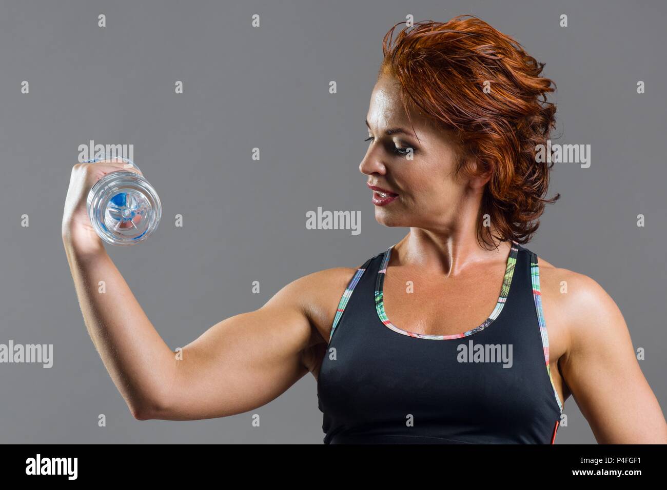 Adult athletic fitness red-haired woman in sports uniform with a bottle ...