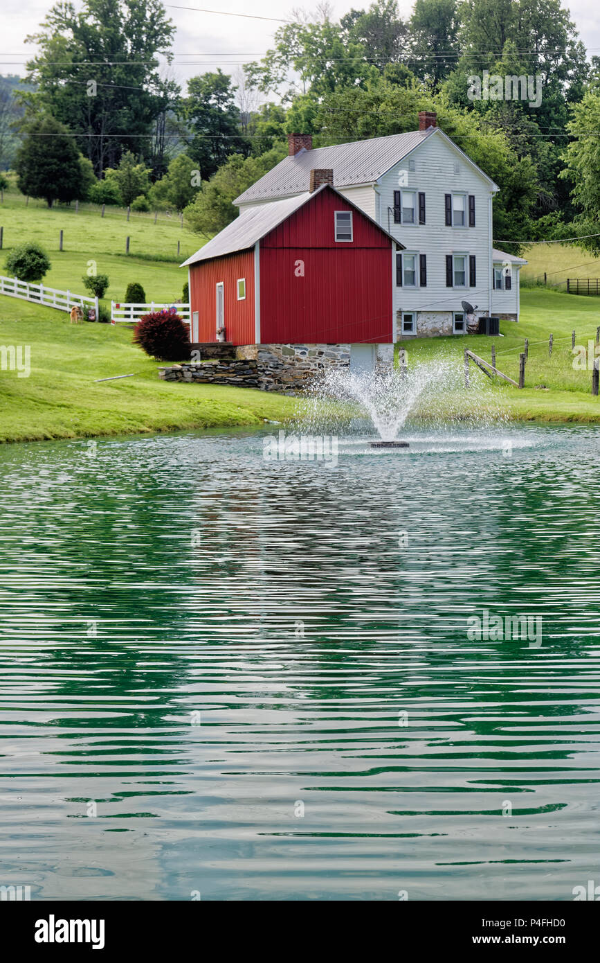 Farm house in summer landscape with large scenic pond and fountain with ...