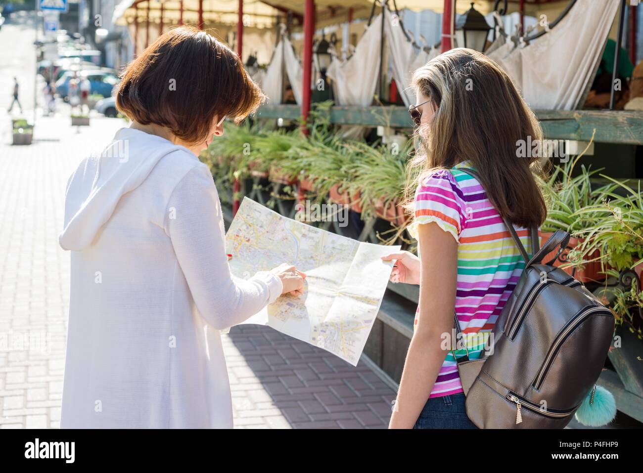 Back view of mom and daughter teen tourist looking at the map on the ...