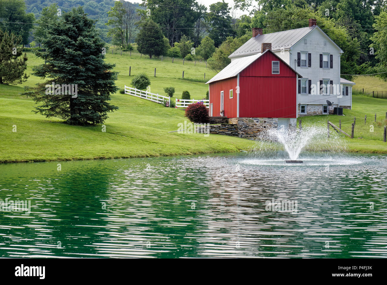 Farm house in summer landscape with large scenic pond and fountain with ...