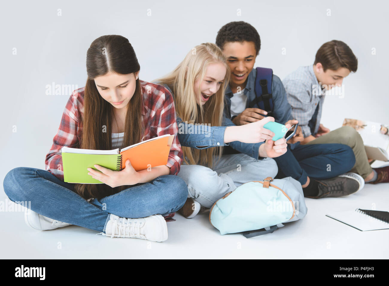 students doing homework while multiethnic friends using smartphones ...