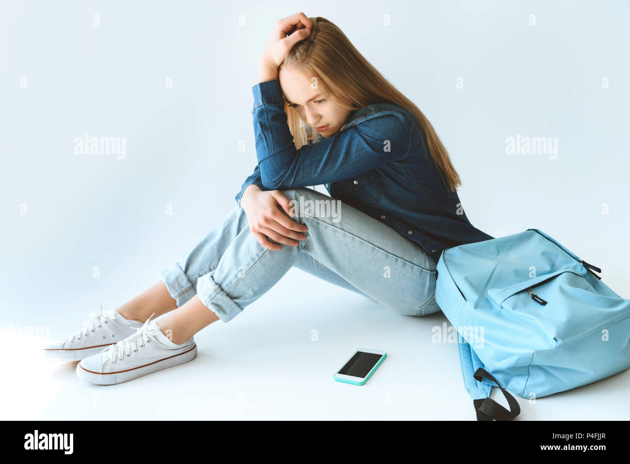 sad caucasian teenage girl with smartphone and backpack isolated on ...