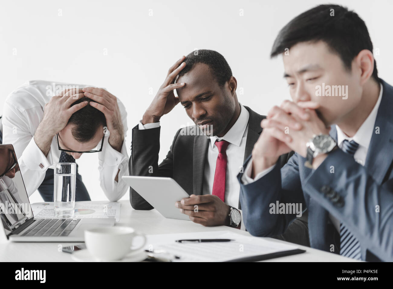 multicultural tired businessmen using tablet together during meeting at ...