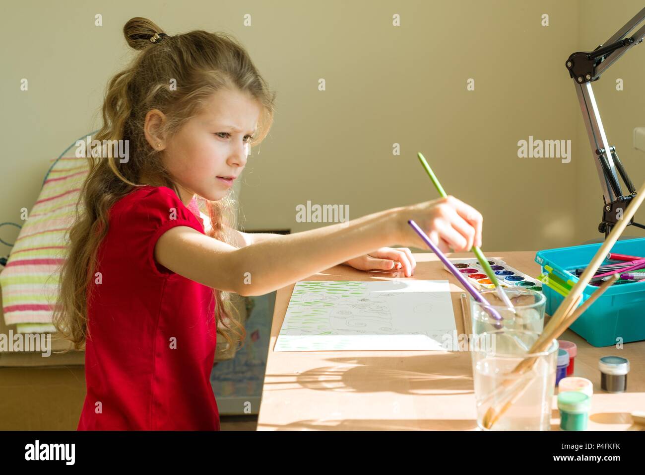 The child is 7 years old, draws watercolor at the table at home. Child ...