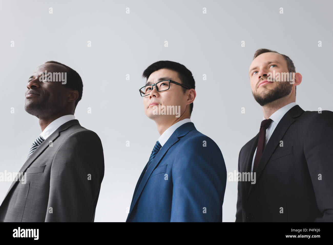low angle view of confident multiethnic young businessmen looking away ...
