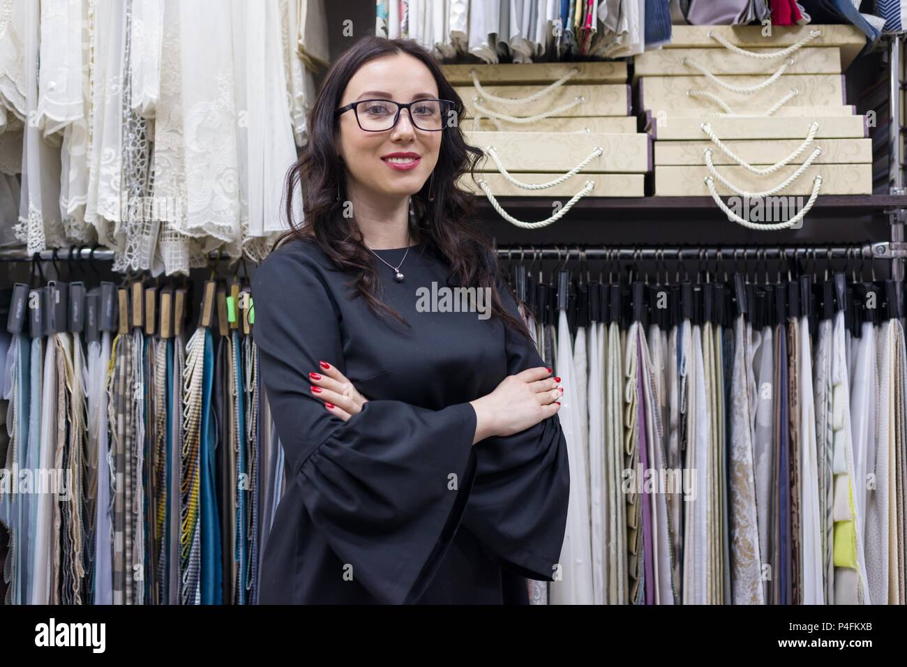 Female seller, interior designer posing in showroom, background of book ...