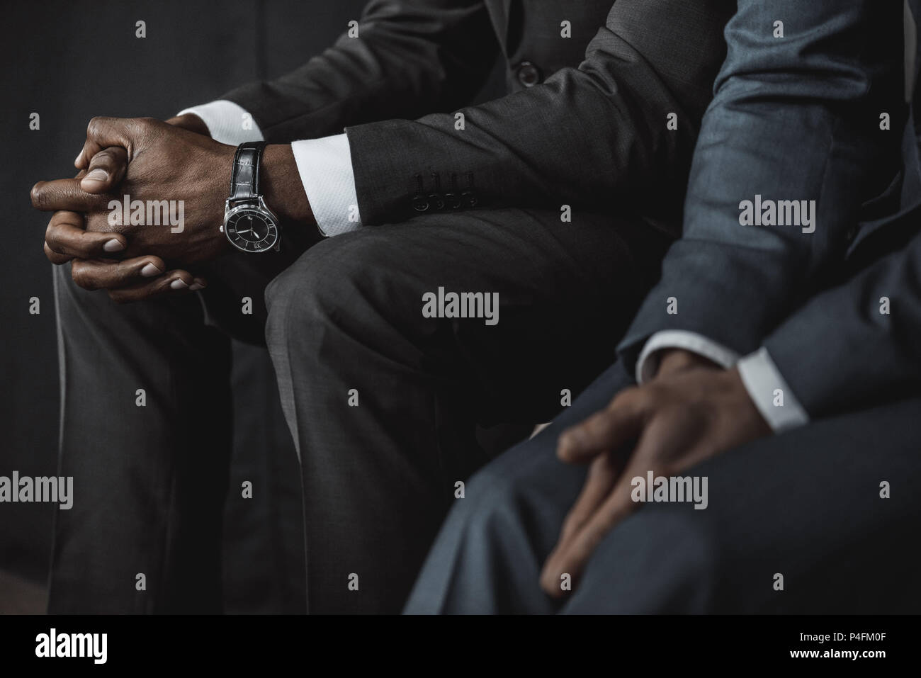 partial view of multiethnic business people in suits waiting for job ...