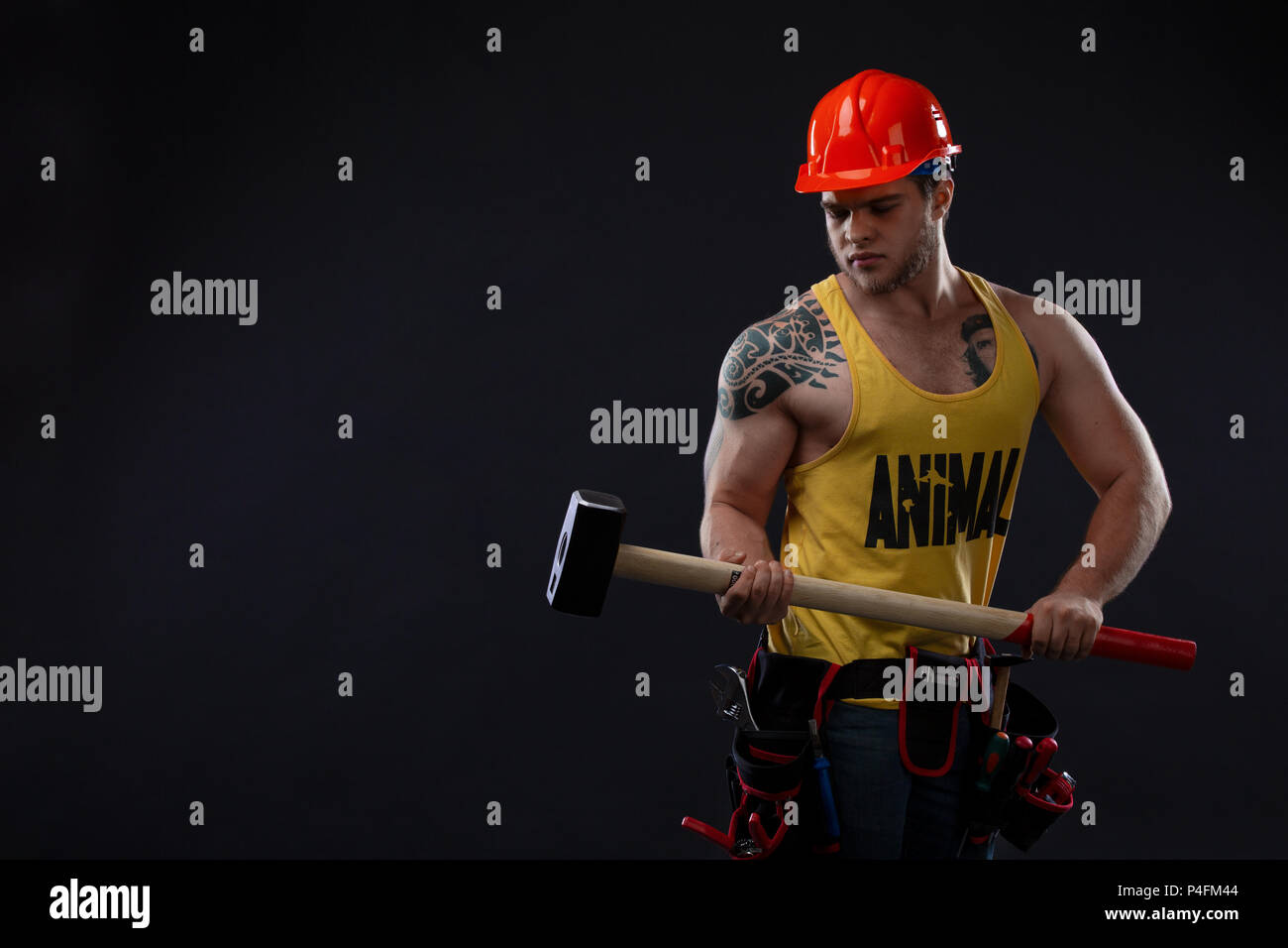 brutal Muscular worker man with a hammer. man in tattoos on a black ...