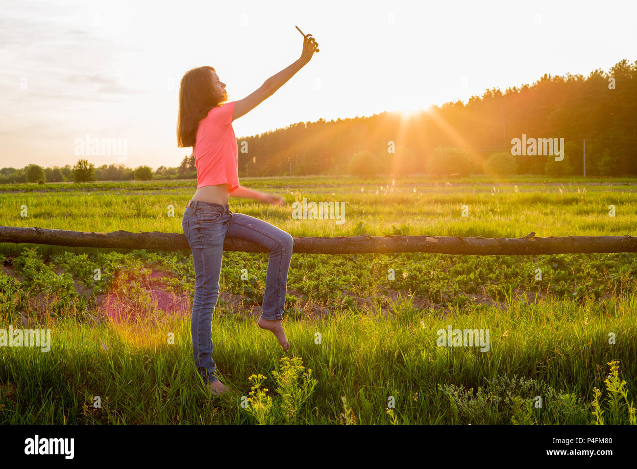 Girl doing selfie on phone on sunset background Stock Photo - Alamy