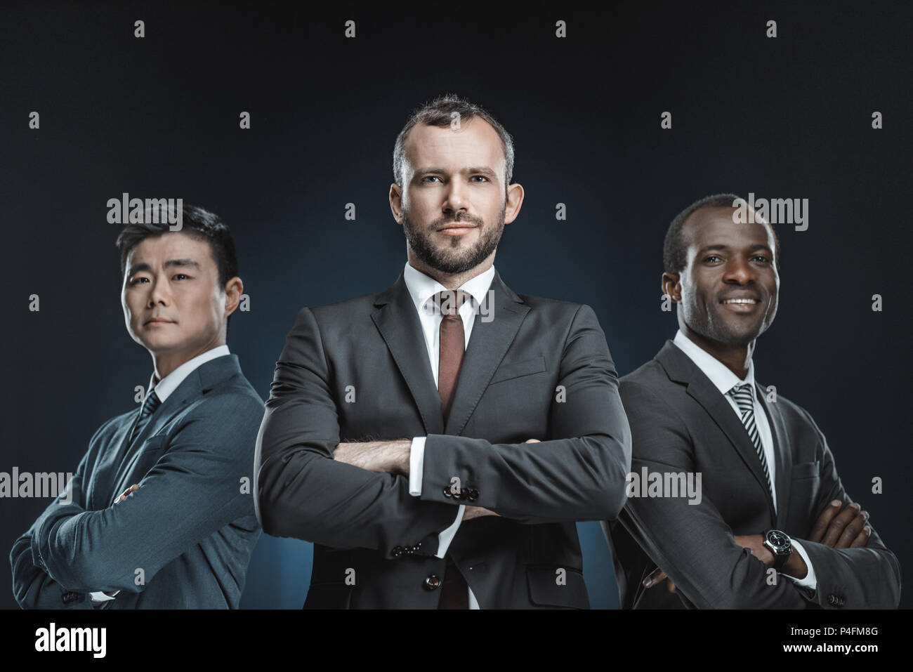 portrait of multicultural group of businessmen in suits looking at ...