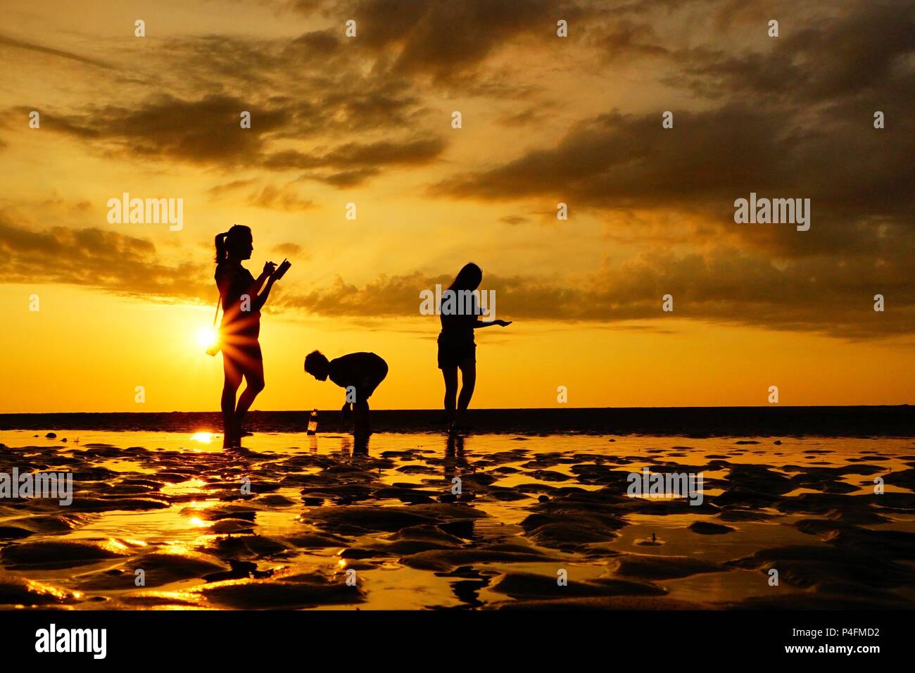 Silhouette of three people play on the beach Stock Photo - Alamy