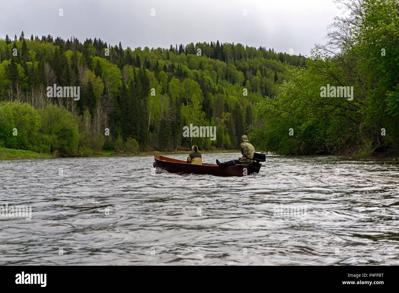 Two people in a traditional wooden flat-bottomed boat with outboard ...