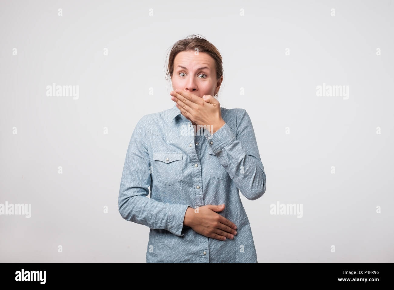 Funny woman closing her mouth with palm hearing funny joke. Trying not ...