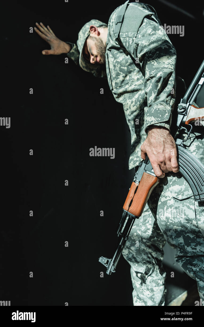 mourning soldier with rifle leaning on wall isolated on black Stock ...
