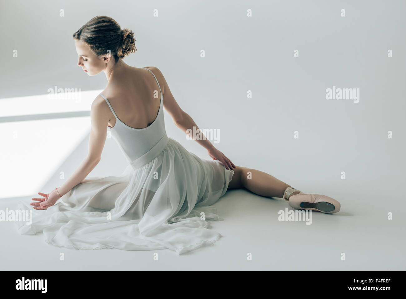rear view of ballerina sitting in white dress and ballet shoes Stock ...