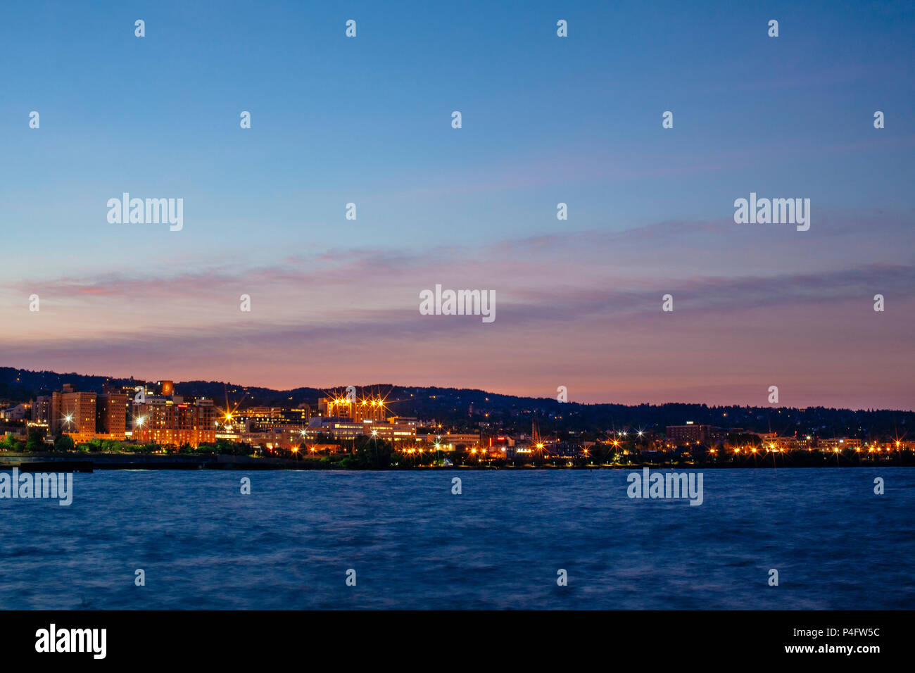 The Duluth, Minnesota skyline illuminated at sunset with crashing waves ...
